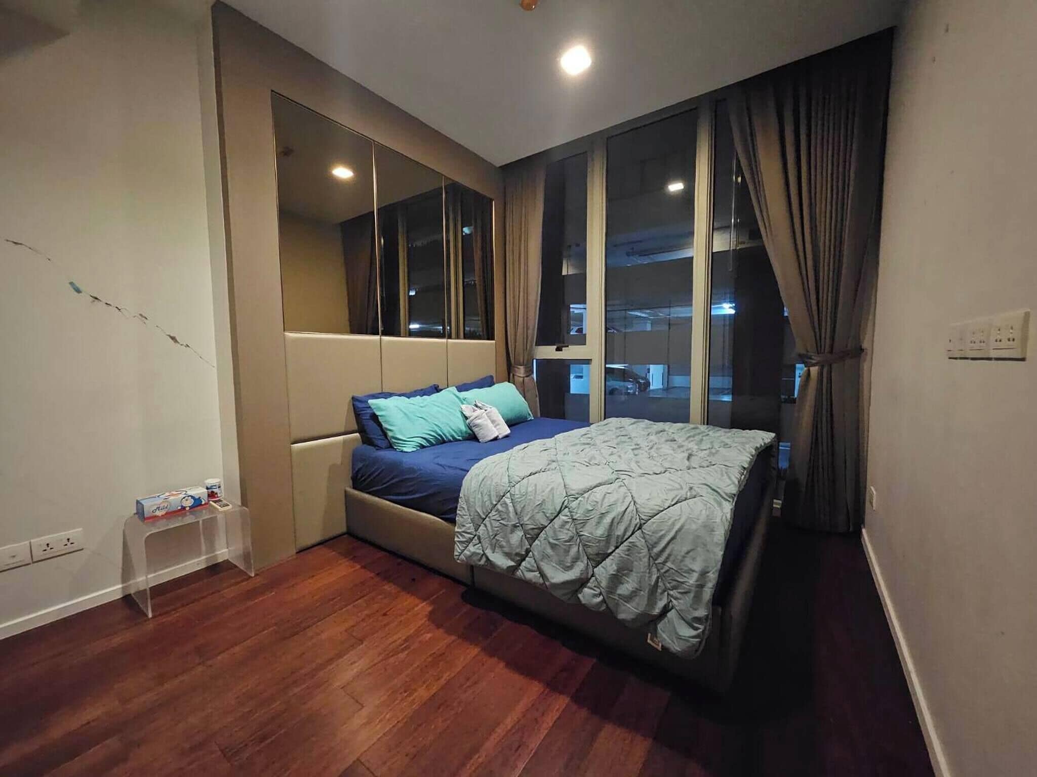 Quarto com cama, mesa de cabeceira, janela e vista exterior.