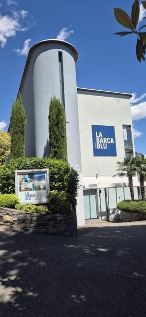 Um edifício moderno com fachada curva, uma placa com a inscrição 'LA BARCA BLU' e entrada de hotel.
