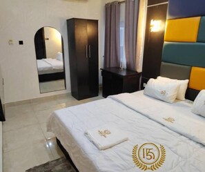 Quarto de hotel com cama, guarda-roupa, espelho e mesa de cabeceira.