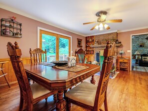 Uma sala de jantar com mesa de madeira, cadeiras e ventilador de teto.