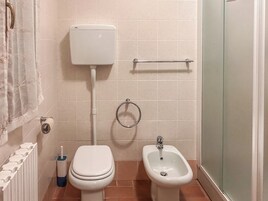 Uma casa de banho com sanita, bidé e um porta-toalhas.