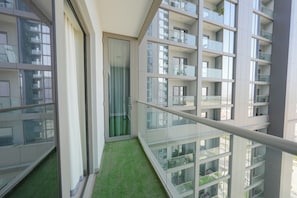 Um edifício de apartamentos moderno com várias varandas, janelas amplas e uma área com grama sintética.