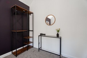 Quarto com guarda-roupa, espelho redondo e uma mesinha com uma planta.