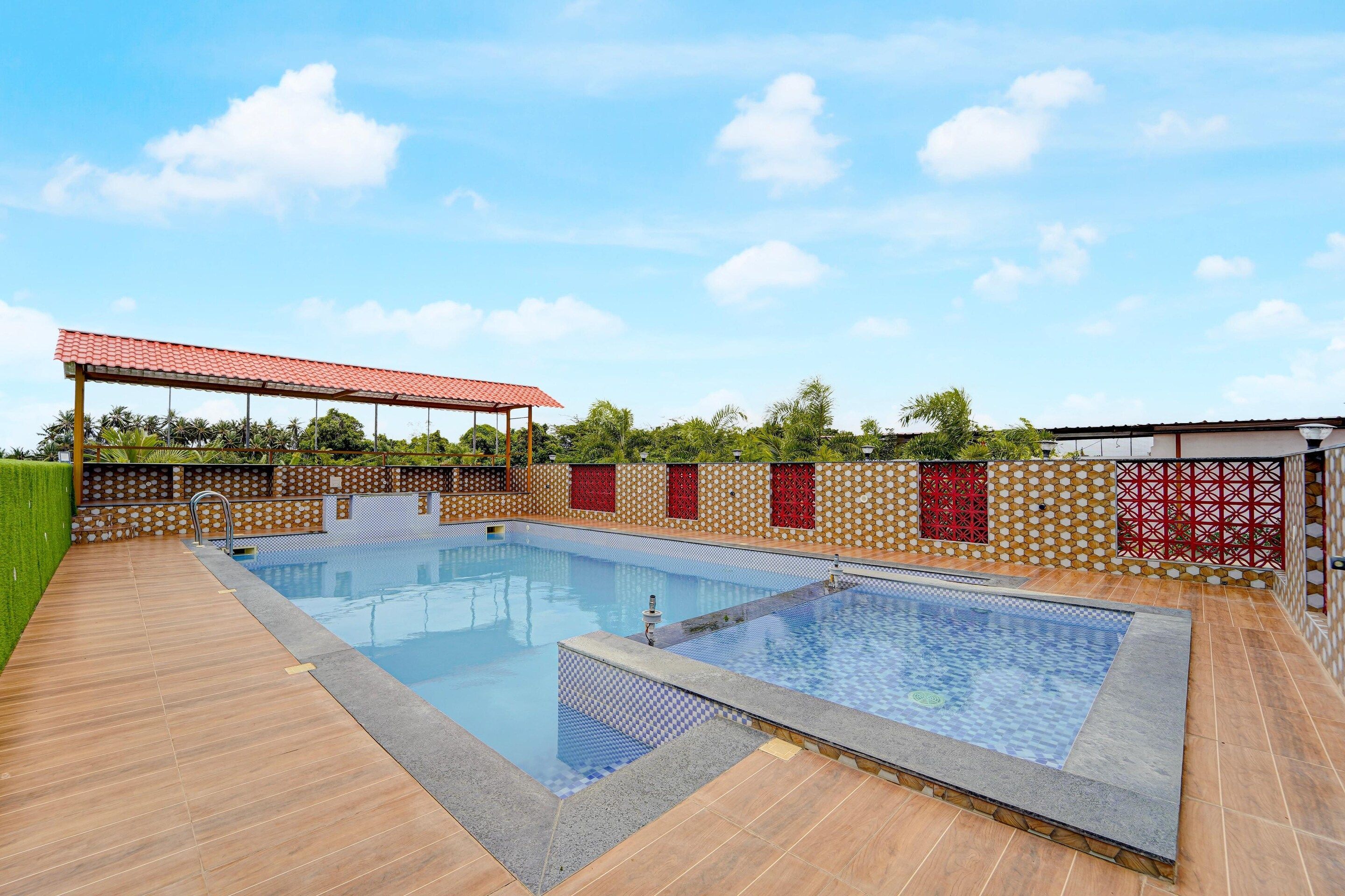 Piscina com deck ladrilhado, área coberta e parede decorativa com padrões geométricos.