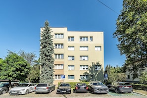 Edifício residencial com vários andares e área de estacionamento na frente.