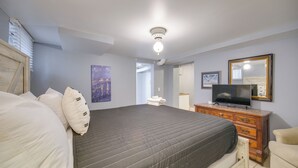 Um quarto com uma cama, cômoda, televisão e obras de arte nas paredes.