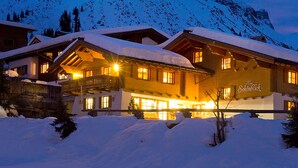 Montanha coberta de neve ao entardecer com um hotel com várias divisões e uma varanda.