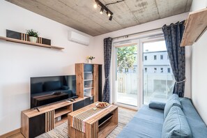 Uma sala de estar moderna com televisão de tela plana, mobiliário de madeira, um sofá e vista para o exterior.