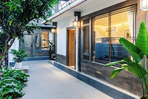 Um edifício moderno com amplas janelas, área externa coberta e plantas em vasos.