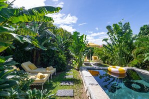 Área da piscina com espreguiçadeiras e uma piscina pequena.