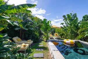 Área da piscina com espreguiçadeiras e uma piscina pequena.