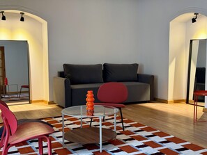 Uma sala de estar moderna com um sofá, uma mesa de vidro e uma cadeira vermelha.