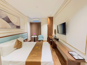 Quarto de hotel com cama, escrivaninha, cadeira, televisão e cortina.