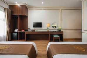 Quarto de hotel com duas camas, uma escrivaninha, televisão, espelho e um pequeno armário.