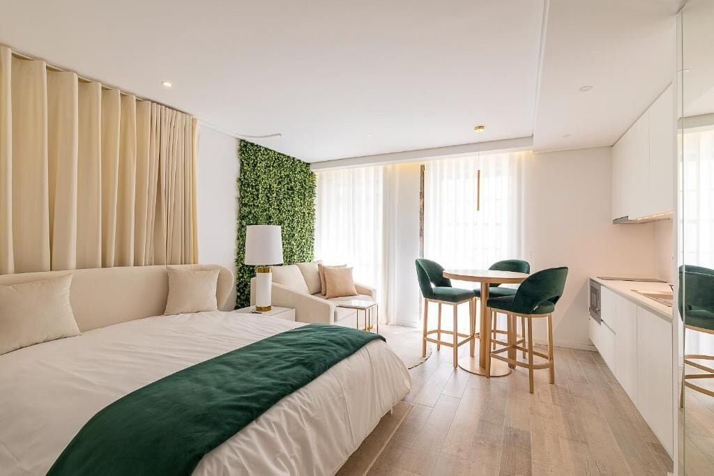 Quarto de hotel moderno com uma cama grande, um espaço pequeno para refeições e uma cozinha compacta.