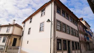 Um edifício de dois andares com fachada branca, várias janelas e telhado em telhas.