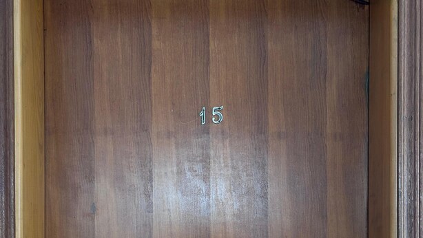 Uma porta de madeira com fechadura de teclado numérico e o número '15' visível.