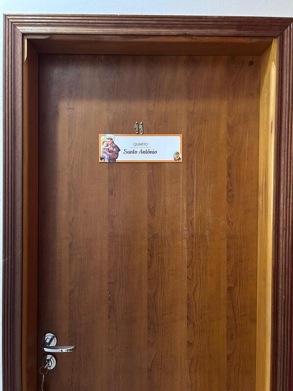 Uma porta de madeira com uma placa indicando 'Quarto Santo Antônio' e o número '11'.