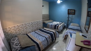 Quarto pequeno e compacto com duas camas, uma escrivaninha e uma cadeira.