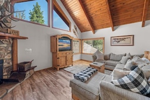 Uma sala de estar acolhedora com lareira, móveis de madeira e uma grande janela com vista para o exterior.