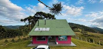 Uma casa térrea com telhado verde, fachada vermelha e um pequeno alpendre.