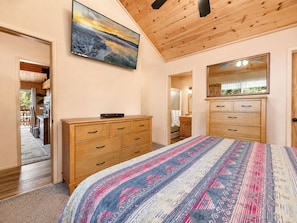 Quarto com cama grande, cómoda de madeira e pintura na parede.