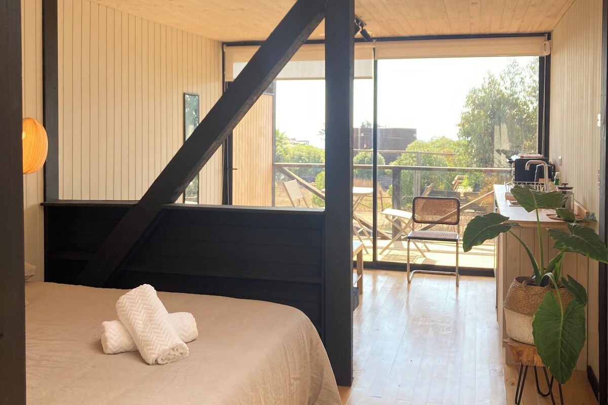 Quarto com cama, claraboia, escada e vista para o exterior.
