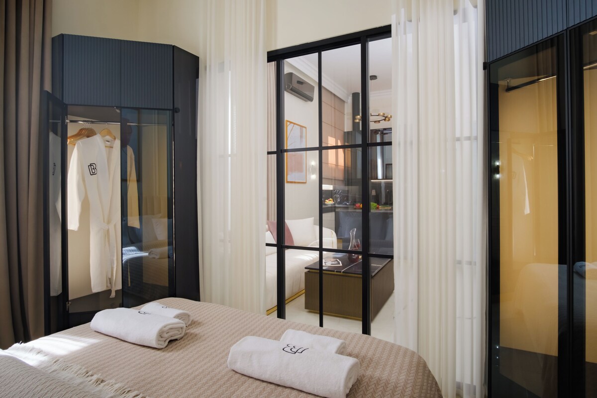 Quarto de hotel com cama, armário, espelho e vista para o banheiro.