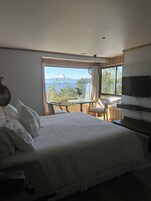 Quarto de hotel com cama, televisão, mesa e cadeira.