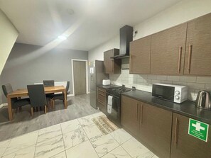 Cozinha com área de jantar, fogão, micro-ondas e armários.