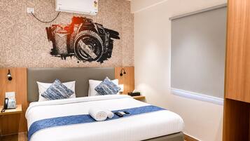 Quarto de hotel com cama, ar condicionado na parede, janela e guarda-roupa de madeira.