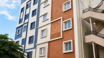 Um edifício residencial de vários andares com design moderno, apresentando uma variedade de estilos de janelas e uma entrada visível com degraus que levam à porta.