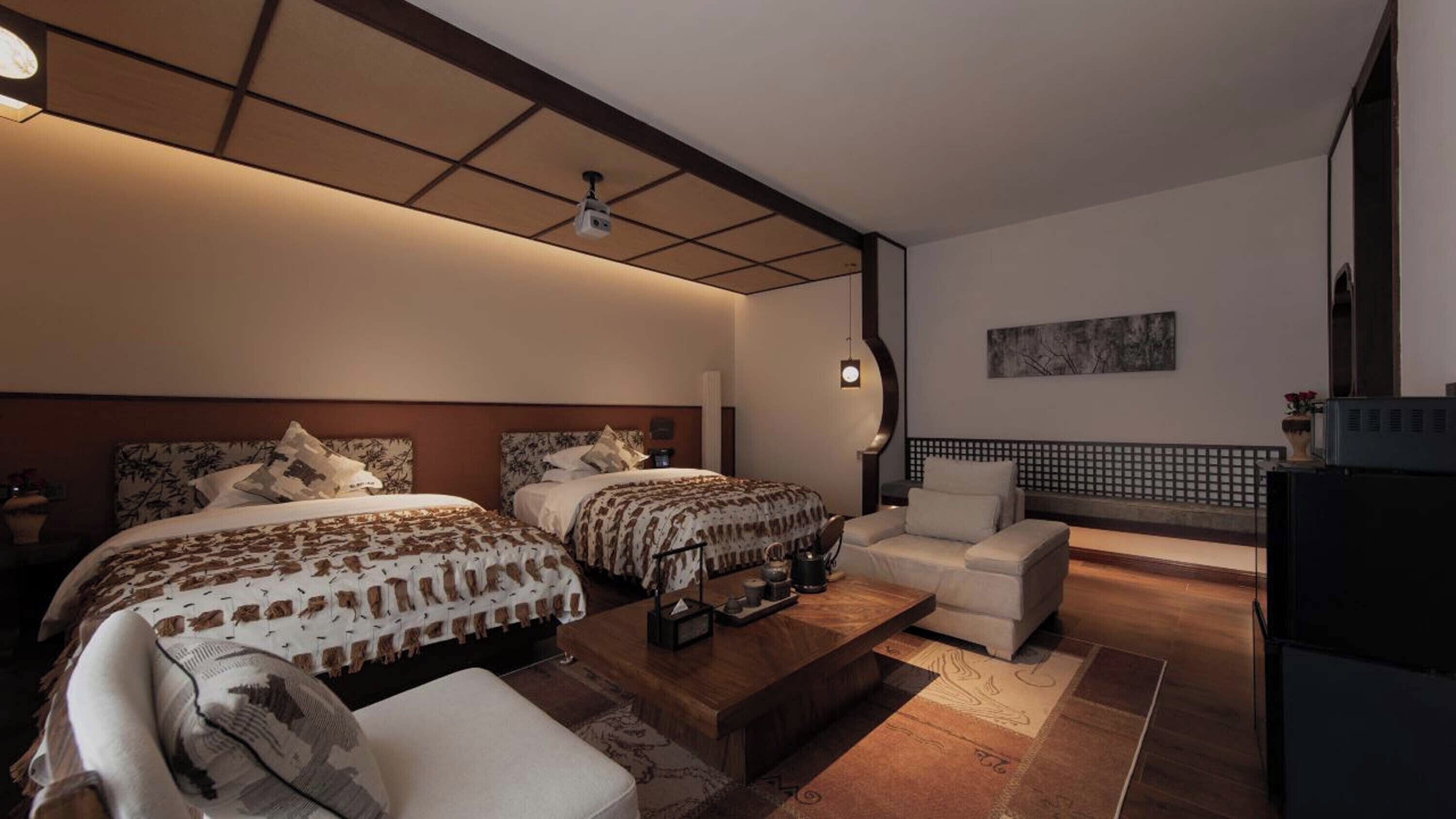 Quarto de hotel com duas camas, um sofá, uma mesa de centro e uma televisão.