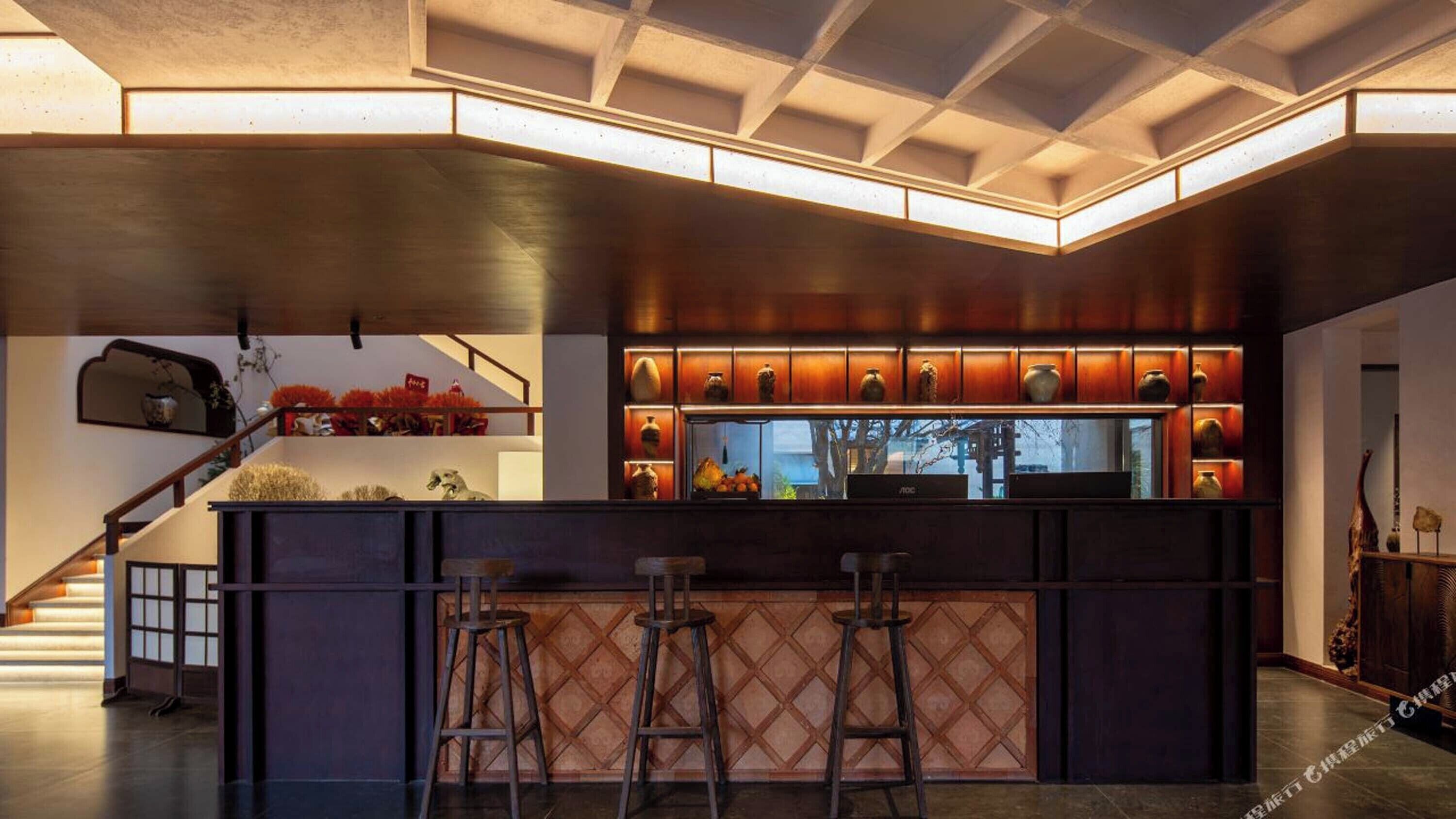 Cozinha moderna com ilha central, banquetas de bar e exposição de objetos decorativos.