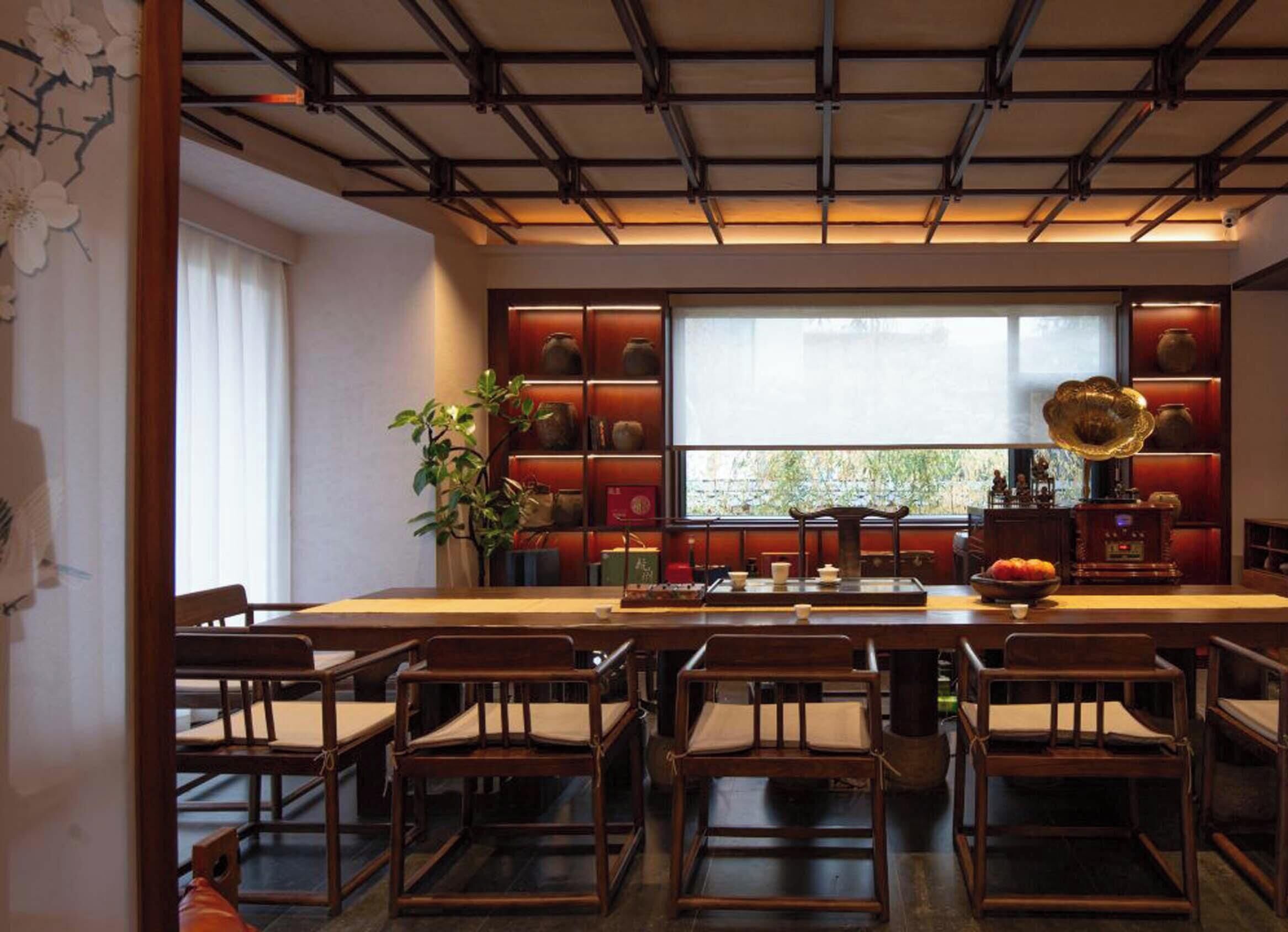 Uma sala de jantar com uma mesa comprida e cadeiras, um vaso de planta e uma janela com vista.