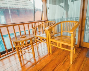 Um deck de madeira com uma mesa e cadeiras, uma porta de vidro e vista para um edifício.