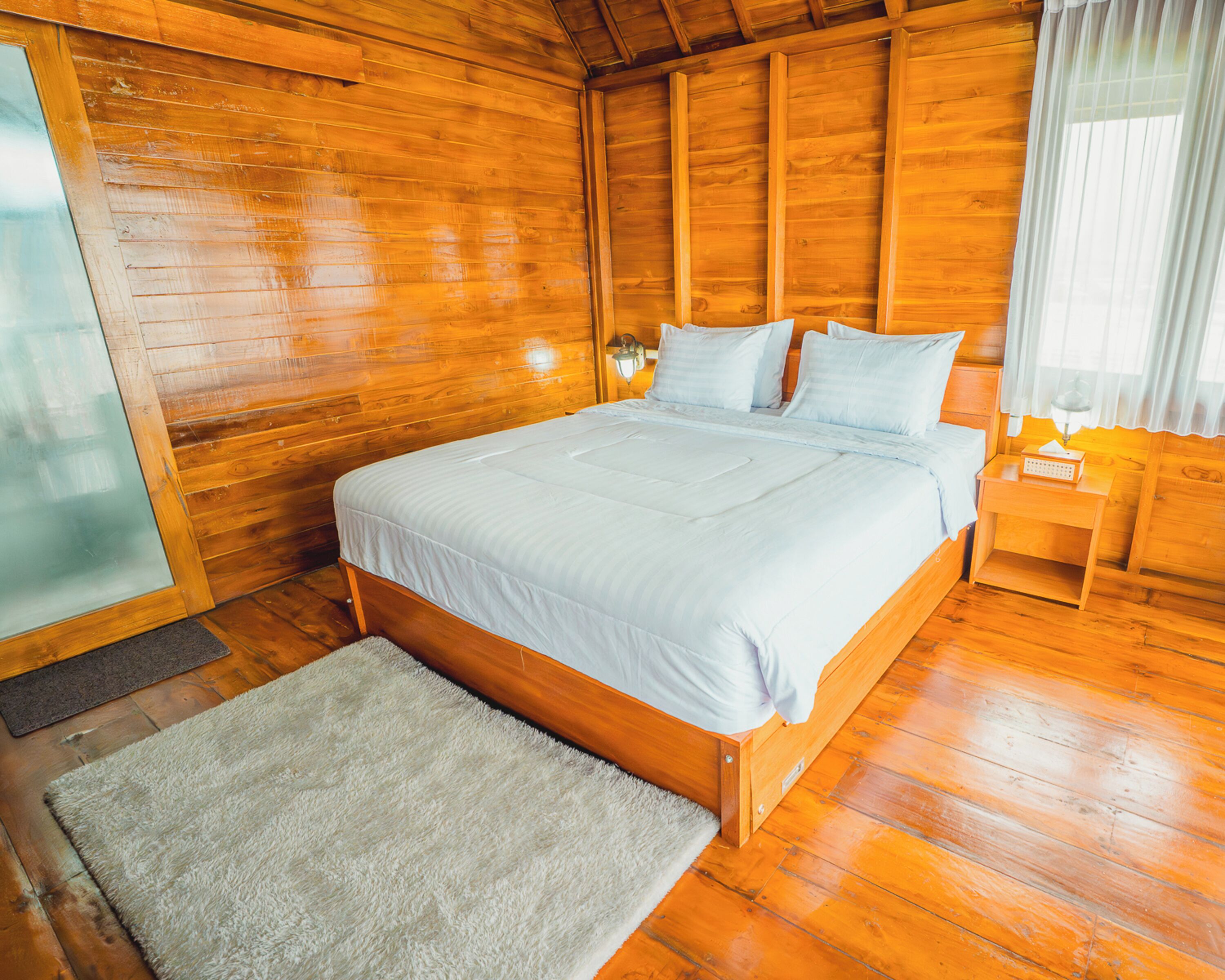 Um quarto com painéis de madeira, uma cama, mesas de cabeceira e um criado-mudo.