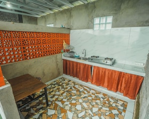 Uma cozinha compacta com painel de azulejos, pia, fogão e uma pequena mesa de jantar.