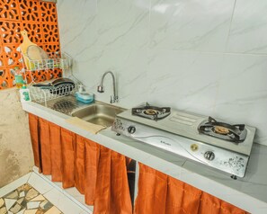 Uma cozinha com pia, fogão e escorredor de louça.