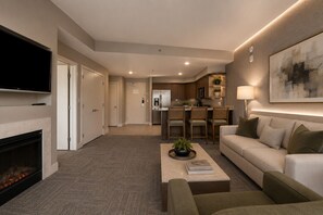 Uma sala de estar moderna com televisão de tela plana, lareira, sofá e uma mesa de centro com um livro e uma planta.