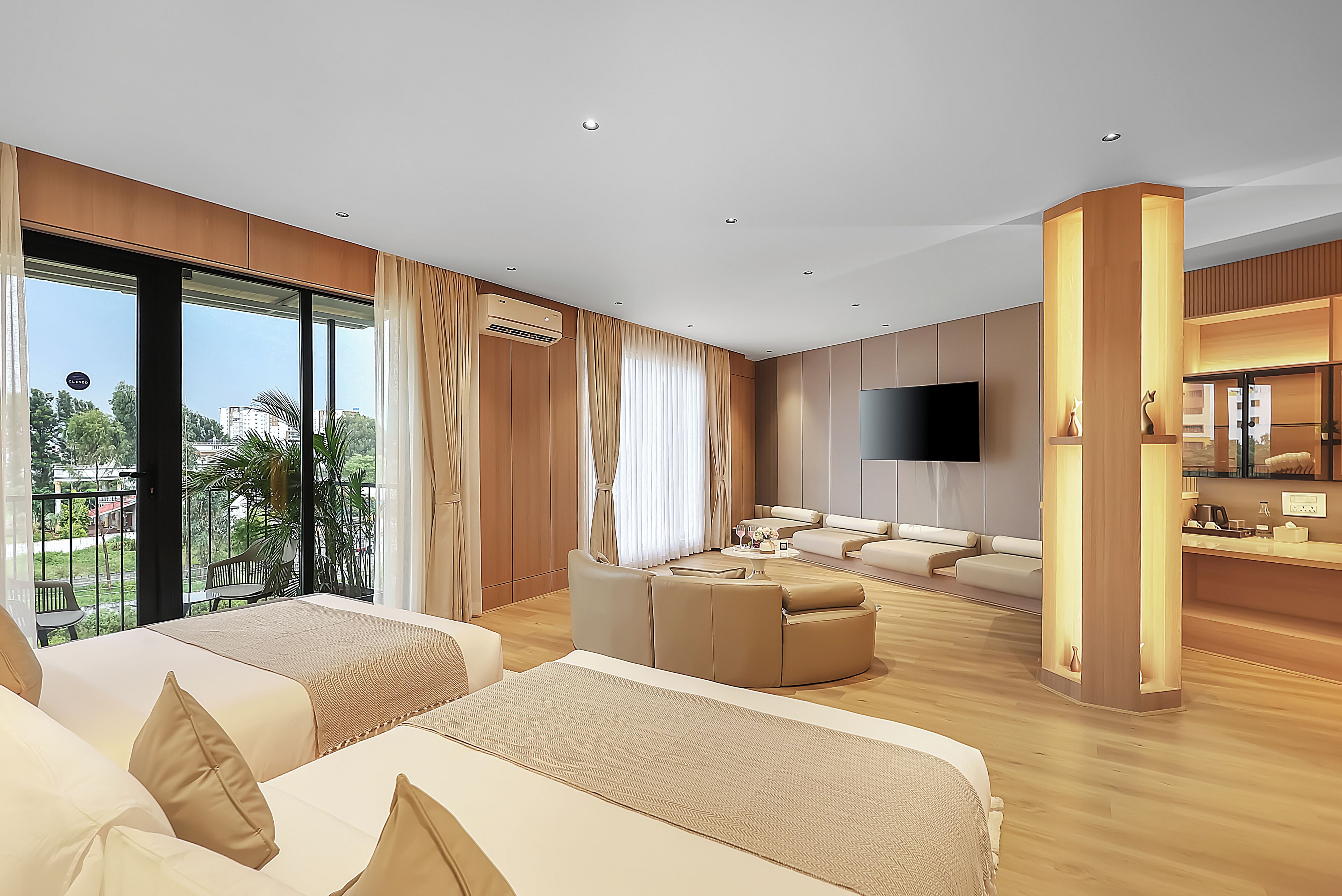 Uma sala de estar moderna com um conjunto de sofás, uma TV de tela plana na parede e uma varanda com vista para a cidade.