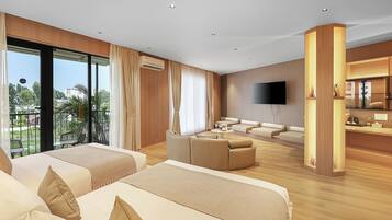 Uma sala de estar moderna com um conjunto de sofás, uma TV de tela plana na parede e uma varanda com vista para a cidade.