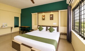 Quarto de hotel com cama, escrivaninha e janela com grades.