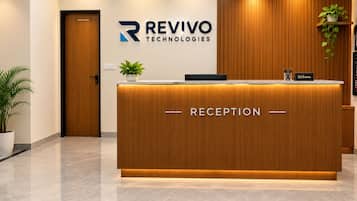 Uma mesa de recepção com uma placa indicando 'RECEPTION', o logotipo de 'REVIVO TECHNOLOGIES' na parede e um vaso de planta no balcão.