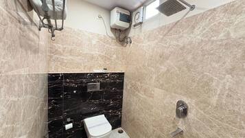 Casa de banho com sanita, toalheiro, chuveiro e unidade de ar condicionado na parede.