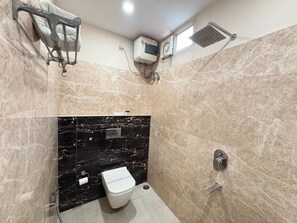 Casa de banho com sanita, toalheiro, chuveiro e unidade de ar condicionado na parede.