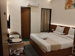 Quarto de hotel com cama, mesa de cabeceira, cadeira e ar condicionado.