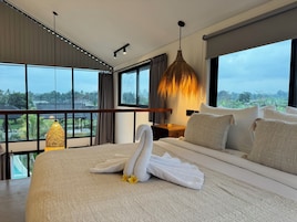 Quarto de hotel moderno com uma cama grande, vista para a paisagem e uma luminária pendente original.