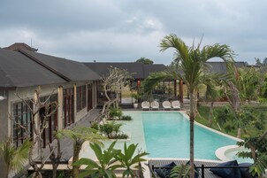Área da piscina com vista clara, espreguiçadeiras e vegetação ao redor.