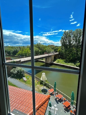 Vista de um rio com uma ponte, área de estar externa e vegetação.